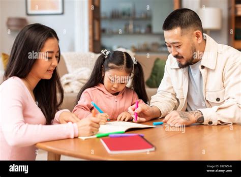Asian Mom And Dad Teaching Preschool Daughter To Write Indoors Stock