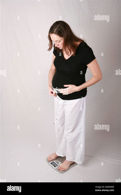 Attractive Young Pregnant Woman In Third Trimester Measures Her Bump