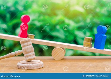 Wooden Figures Of A Man And A Woman Stand On The Scales And Coins