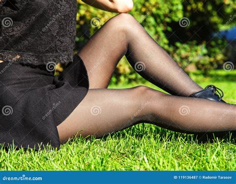 Gambe Di Una Giovane Donna In Calze Nere Che Si Siedono Sullerba