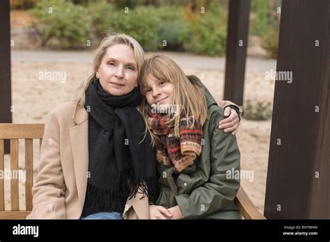 Portrait Affectionate Mother And Daughter Hugging On Park Bench Stock
