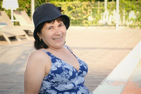 Premium Photo Mature Woman In Swimsuit Sits On The Side Of The Pool