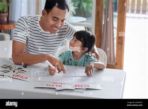 Happy Asian Father Teaching Letter To Her Daughter At Home Read And
