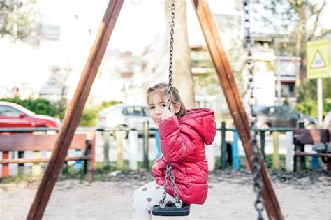 Premium Photo Portrait Of Girl Sitting On Swing At Park