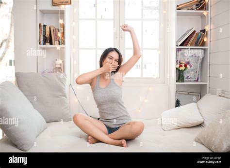Tired Sleepy Asian Woman Waking Up And Stretching While Sitting In Bed