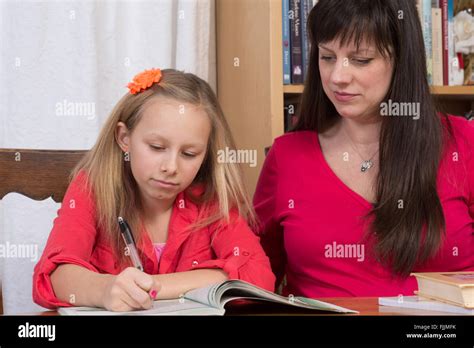 Une Jeune Fille Fait Ses Devoirs Comme Sa Mère Les Regarde Photo Stock