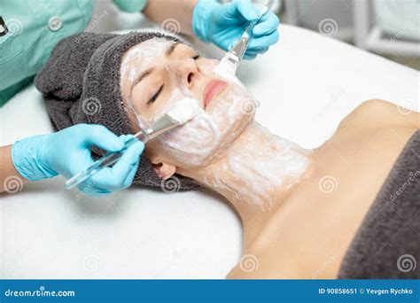 Beautician Applies Face Mask On Beautiful Young Woman In Spa Salon