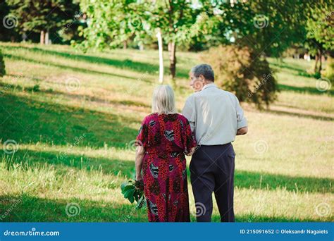 Age Couple In Love Holding Hands On A Walk In The Park In Summer Stock
