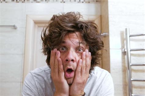 Sleepy Shaggy Young Man Looks At The Mirror In Bathroom In The Morning