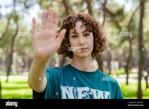 Young Redhead Serious Woman Wearing Green T Shirt Standing On City Park
