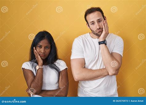Interracial Couple Standing Over Yellow Background Thinking Looking