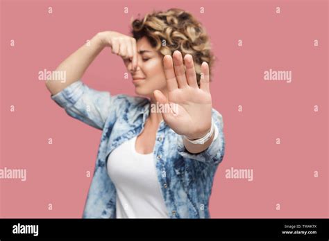 Bad Smell Blocking Portrait Of Dissatisfied Young Woman With Curly