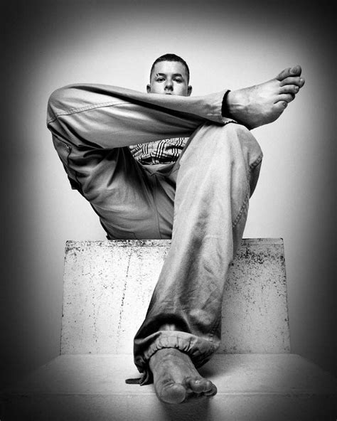 A Man Sitting On Top Of A Cement Block With His Feet Up In The Air