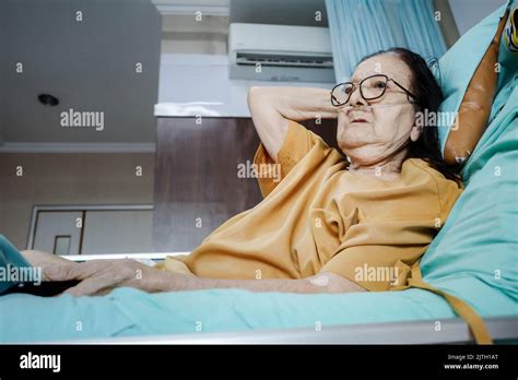 Sick Southeast Asian Female Elderly Patient Relaxing In Bed During