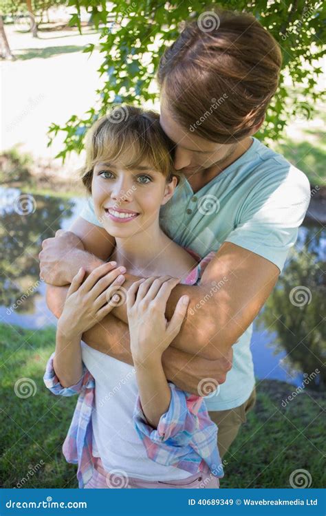Affectionate Young Couple Standing Together In The Park Girl Smiling At