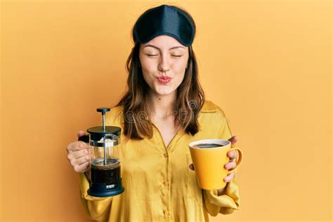Young Brunette Woman Wearing Sleep Mask And Pajama Drinking A Coffee