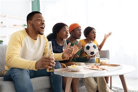 Emotional African American Friends Watching Football Game On Tv Stock