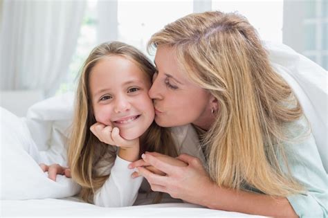Premium Photo Mother Kissing Her Daughter On The Cheek In The Bed