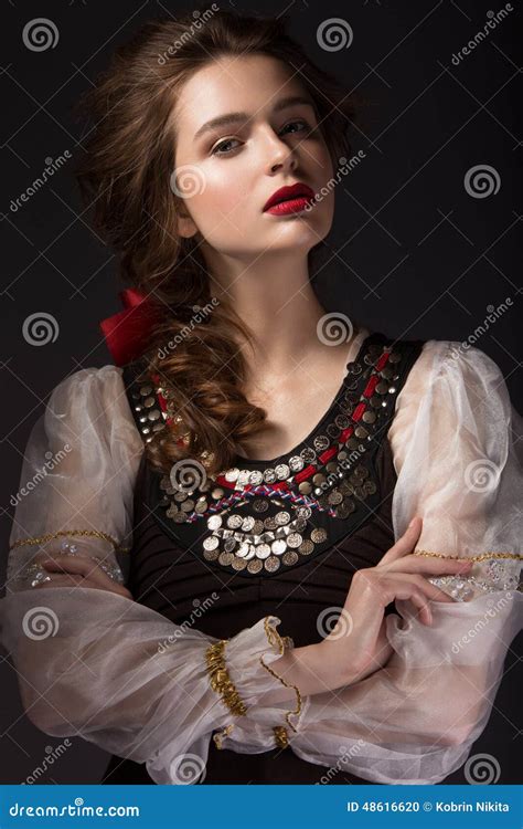 Beautiful Russian Girl In National Dress With A Braid Hairstyle And Red