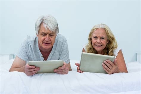 Premium Photo Senior Couple Using Digital Tablets While Relaxing In