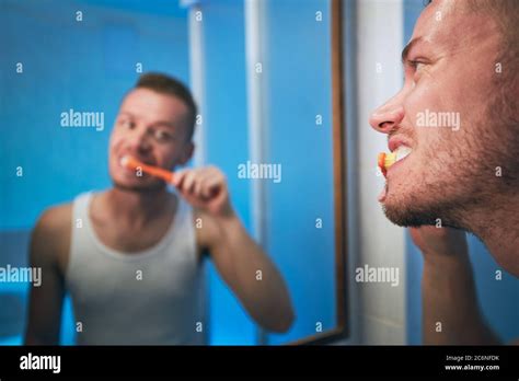 Morning Hygiene Routine Man Brushing Teeth And Looking In Mirror Of