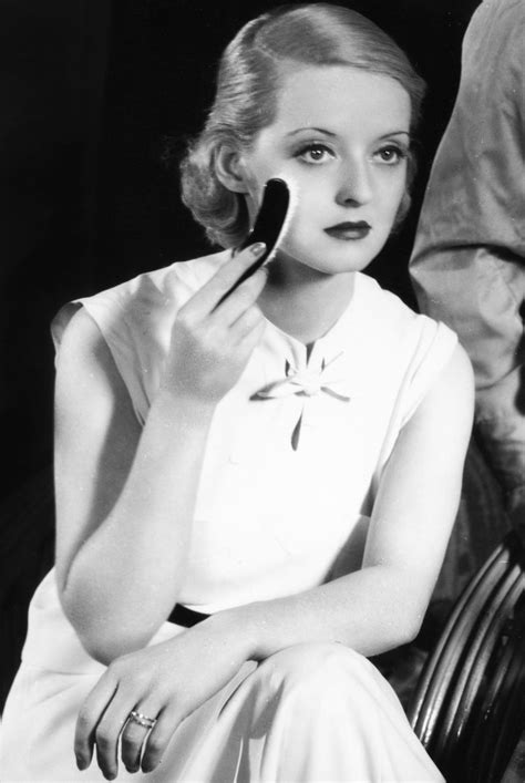 A Black And White Photo Of A Woman Holding A Cell Phone To Her Face