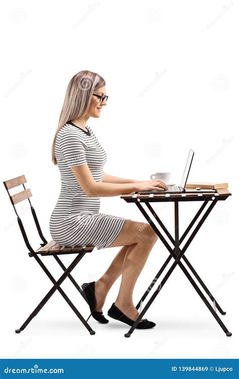 Young Woman Sitting At A Table With Coffee And Working On A Laptop