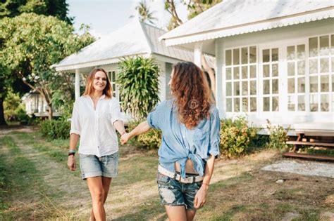Happy Lesbian Couple Walking In The Garden At Their Country House Stock