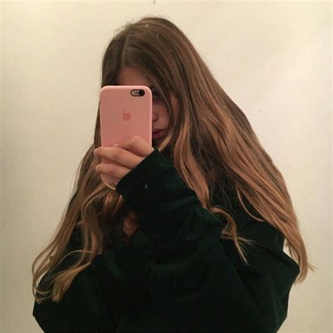 A Woman Taking A Selfie With Her Cell Phone In Front Of Her Face And