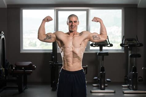 Jovem De Pé Forte Na Academia E Flexionando Os Músculos Muscular
