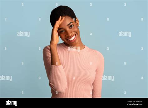 Portrait Of Shy African American Woman Smiling And Touching Head In