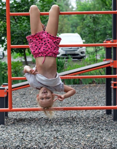 Girl 6 7 Years Old Is Playing Cheerfully On The Playground Hanging