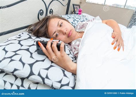 Fille De Jeune Adolescent Se Situant Dans Le Lit Avec Son Téléphone
