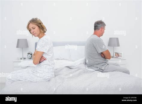 Couple Sitting On Different Sides Of Bed Not Talking After Fight Stock