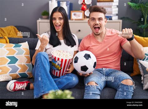 Young Hispanic Couple Football Hooligans Holding Ball And Eating