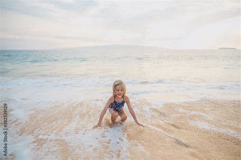 Cute Young Girls Playing In Water On Tropical Beach In Bathing Suit
