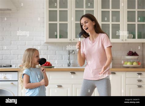 Mother Dancing With Daughter Holding Soup Ladle Like Microphone Singing
