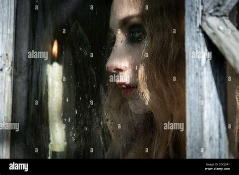 Beautiful Sad Young Girl Looking Out The Window With A Candle Good For