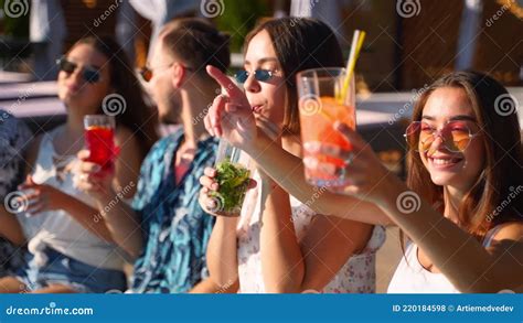 Friends Having Fun At Poolside Party Clinking Glasses With Colorful
