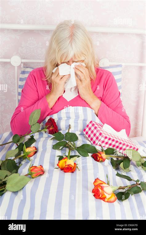 Sad Woman In Pink Pajama Sitting In Bed With A Bunch Of Roses And
