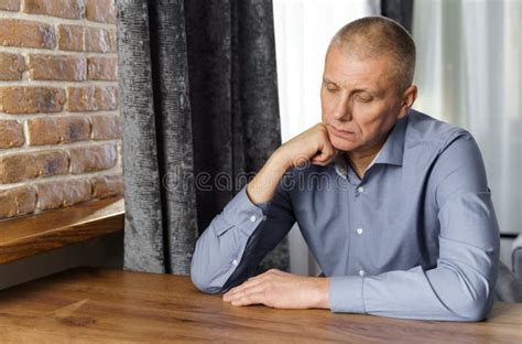 Portrait Of A Pensive Middle Aged Man Sitting At A Table Stock Image