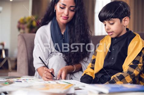 تلميذ سعودي خليجي يدرس في المنزل مع والدته ، تساعده على تأدية واجباته