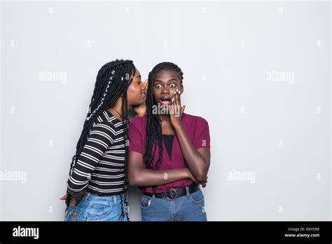 Portrait Of Two Happy Young African Women Sharing Secrets Over White