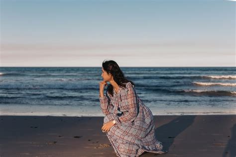 Premium Photo Full Length Of Woman Crouching At Beach Against Sky