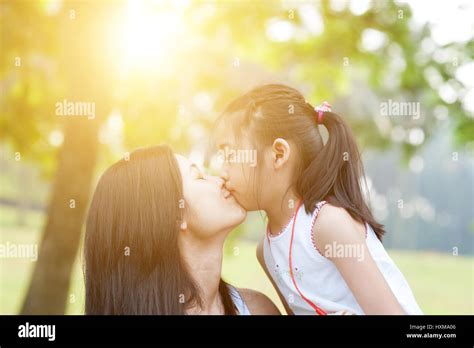 Lifestyle Portrait Mom And Daughter Kissing In Happiness At The Outside