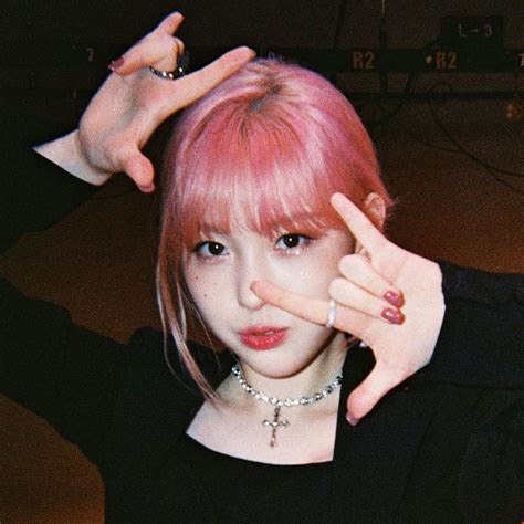 A Woman With Pink Hair Making The Peace Sign While Wearing A Black