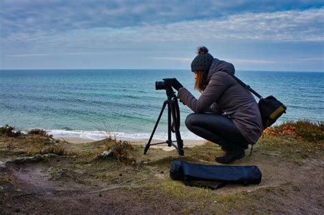 Premium Photo Side View Of Woman Photographing Sea While Crouching At