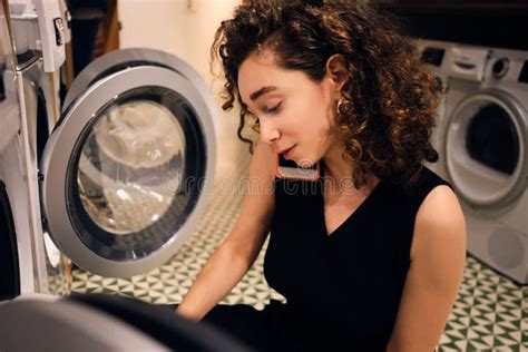 Beautiful Brunette Girl Talking On Smartphone Washing Clothes In Self