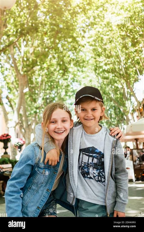 Portrait Of Smiling Brother And Sister Standing Arm Around In City