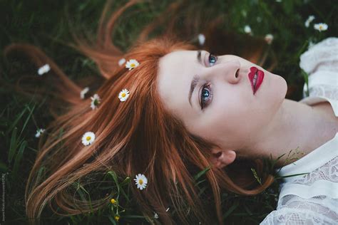 Ginger Haired Woman Laying On Grass With Chamomile In Her Hair By
